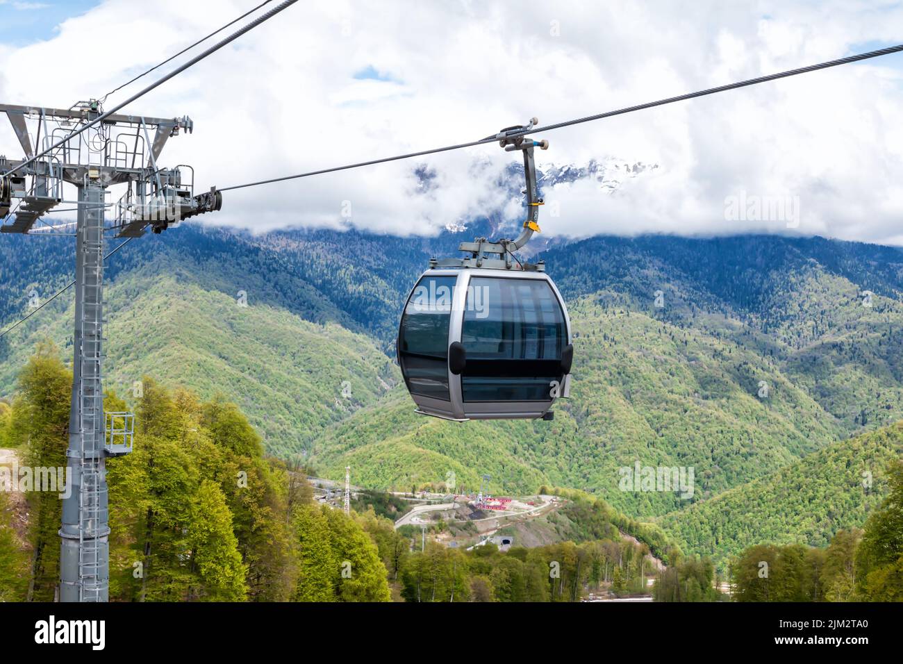 Aerial lift against the backdrop of a green forest and snow-capped ...