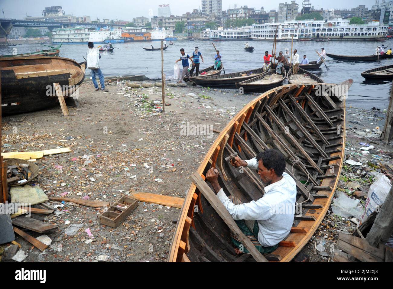 Worker repairs a wooden boat along the banks of the Buriganga river in ...