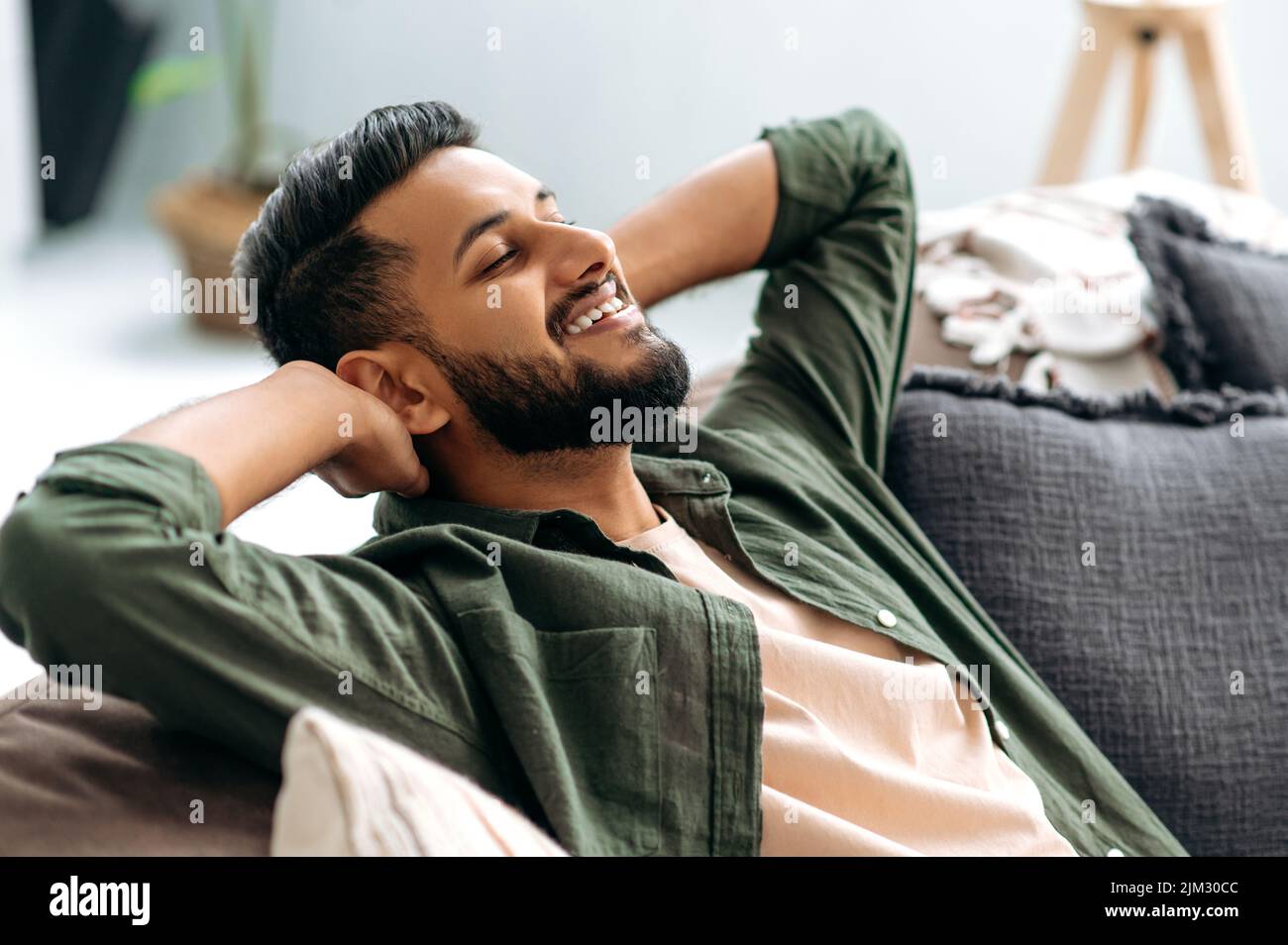 Relaxed satisfied calm mixed race guy in casual shirt, resting on the ...