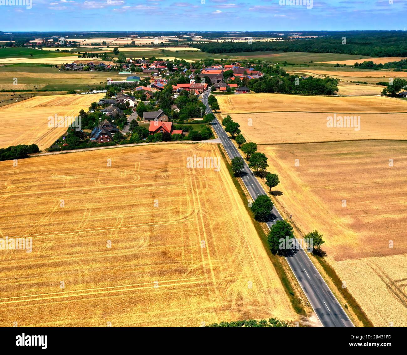 Aerial view of harvested wheat fields with a country road leading to a ...