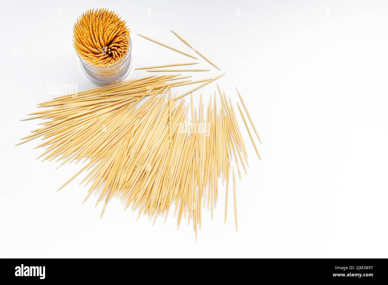 Pile of round wooden toothpicks and toothpick box with a plastic cover ...