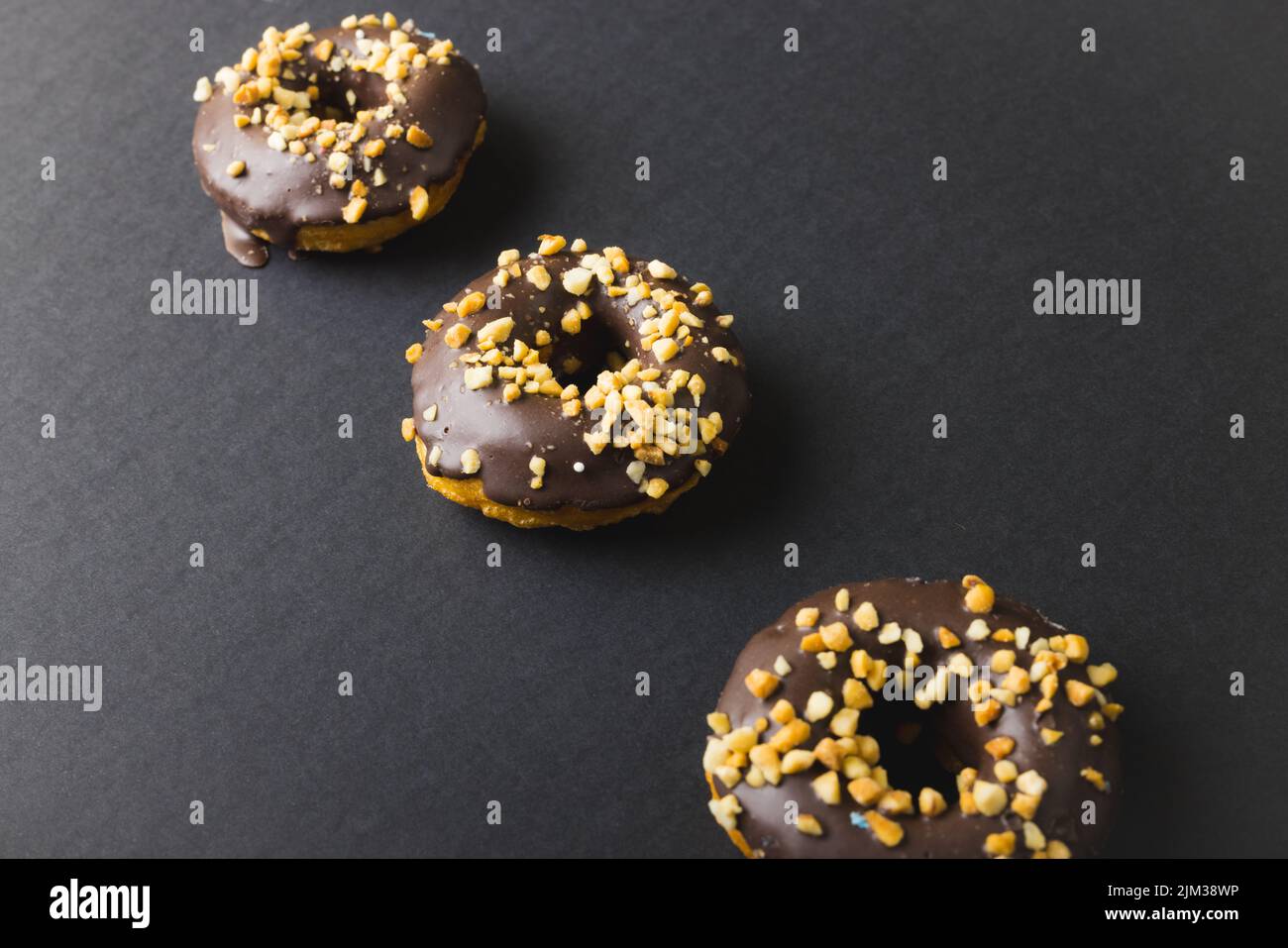 High angle view of fresh chocolate donuts with crumbs amidst copy space ...