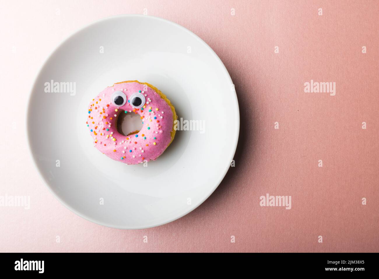 Directly above view of fresh donut with googly eyes in white plate by ...