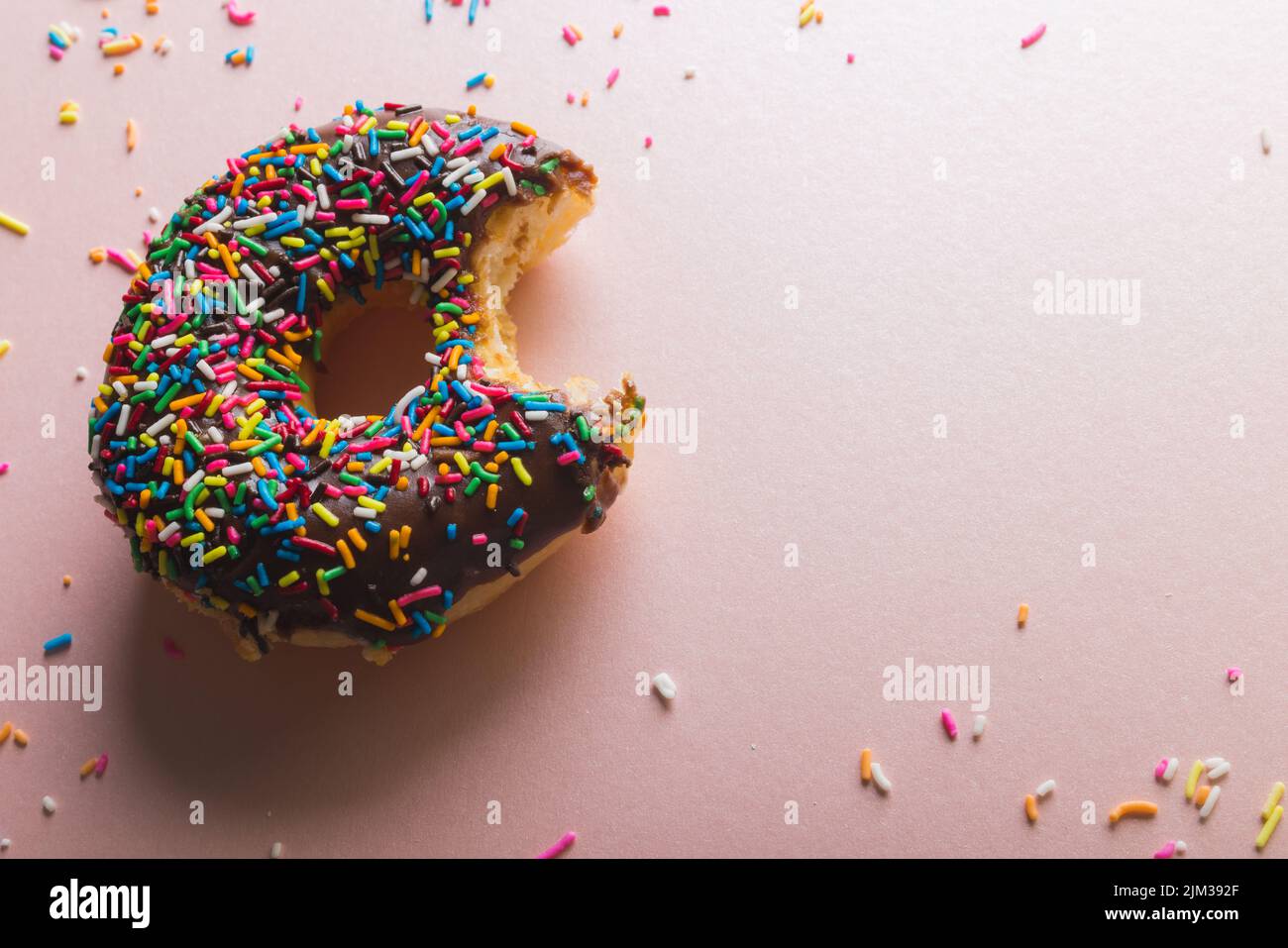 Overhead view of missing bite of chocolate donut with sprinklers by ...