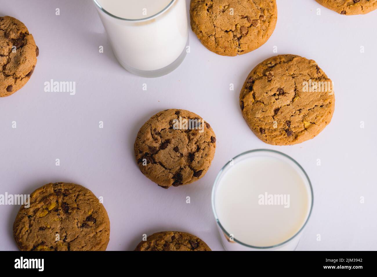 Overhead view of milk in glasses with cookies over white background ...