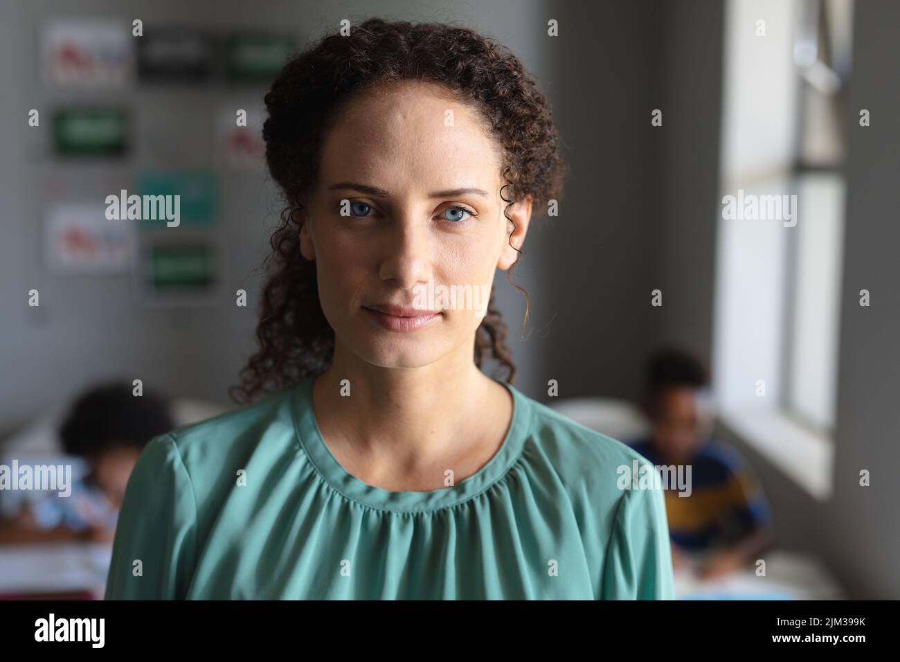 Close-up portrait of young female teacher with gray eyes standing in ...
