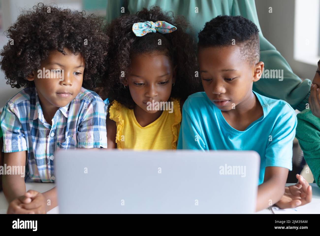 African american elementary students using laptop while sitting at desk ...