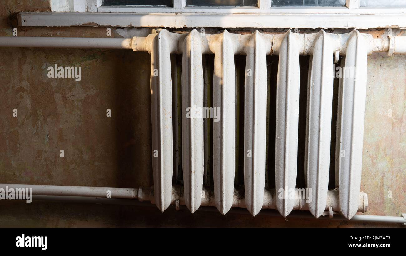 Old vintage cast iron radiator and pipes covered with white paint ...