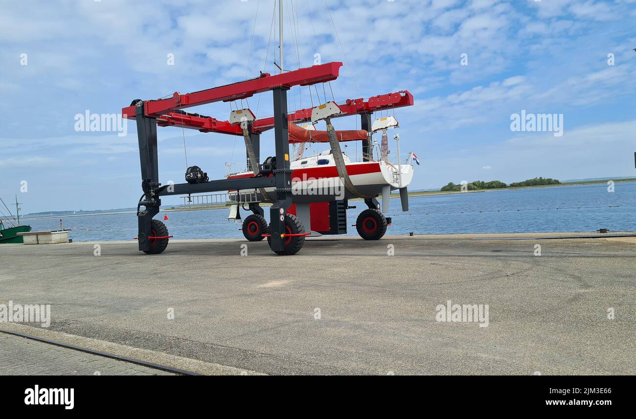 Boat being pulled out of the water with large cranes to a shipyard ...