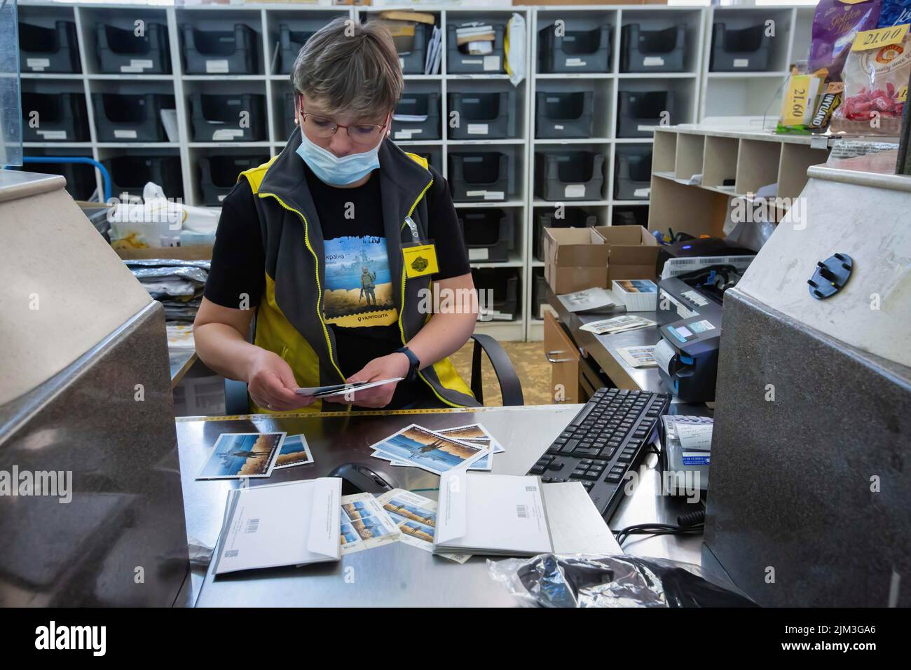 A postal worker sells postage stamps and postcards from a new series ...