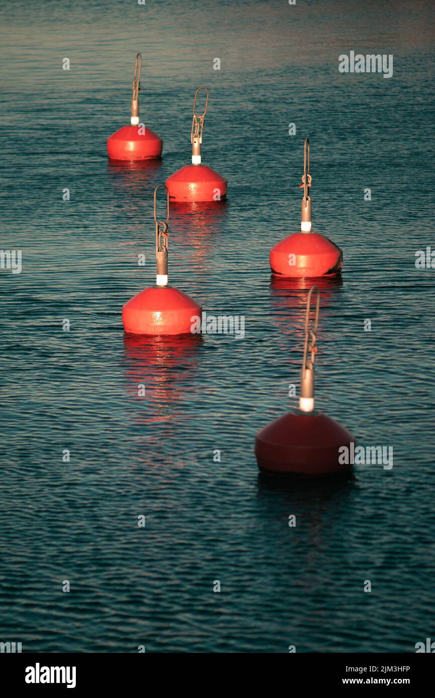 A vertical shot of red buoys floating on blue sea water Stock Photo - Alamy