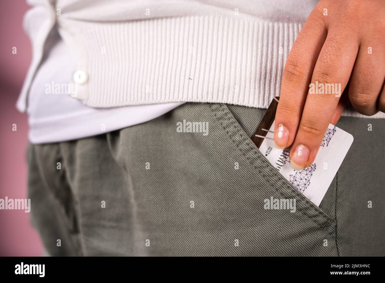 A woman leaving a credit card in her pocket against a pink wall Stock ...