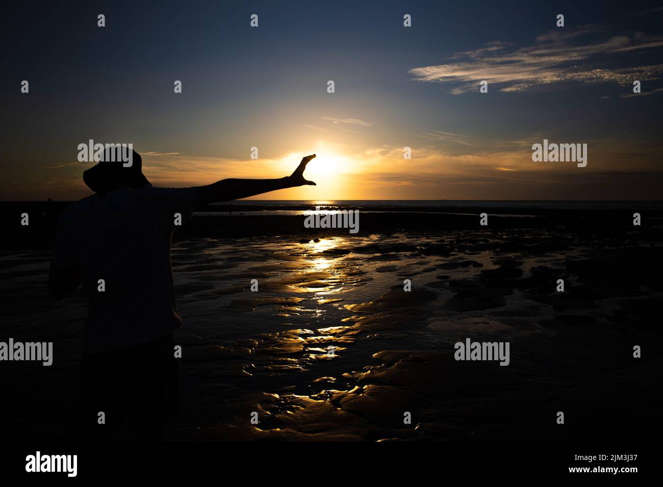 A silhouette of a person posing under a sunset sky on the Caota dune ...