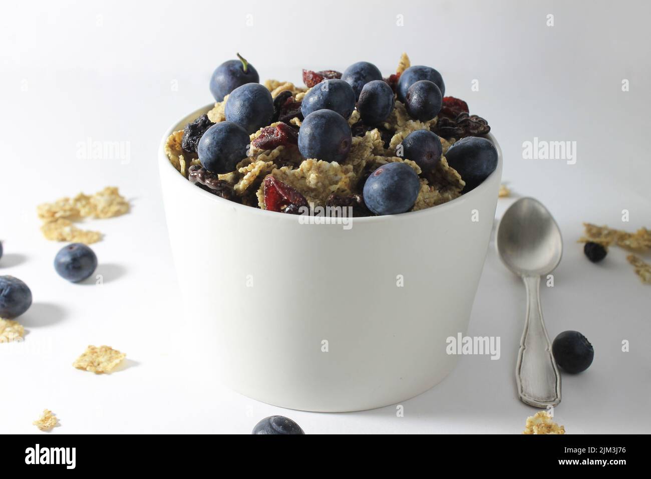 grains flakes with blueberry inside white bowl, with spoon next to it ...
