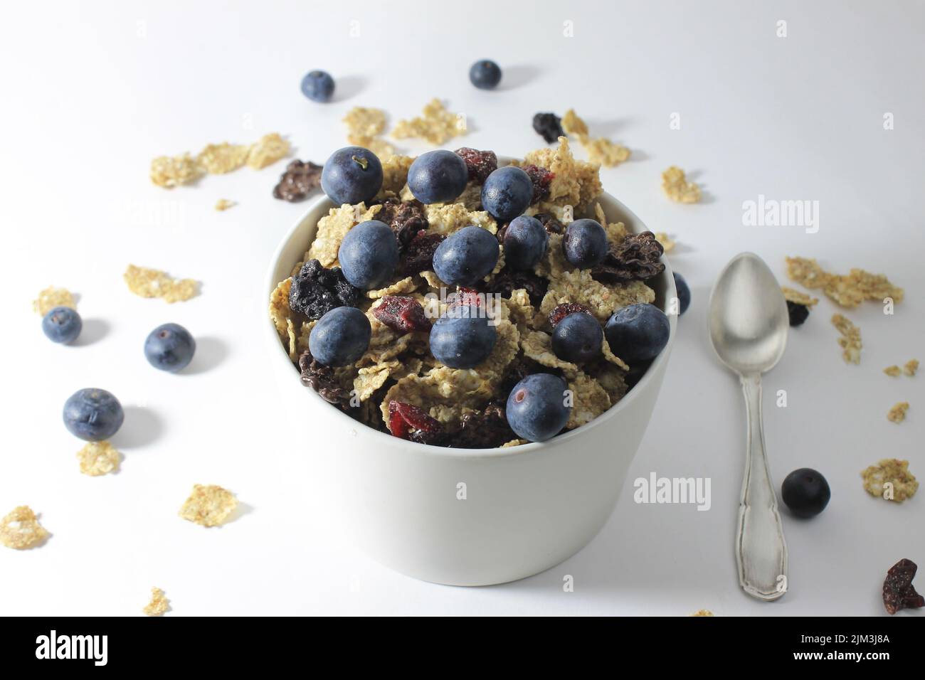 grains flakes with blueberry inside white bowl, with spoon next to it ...