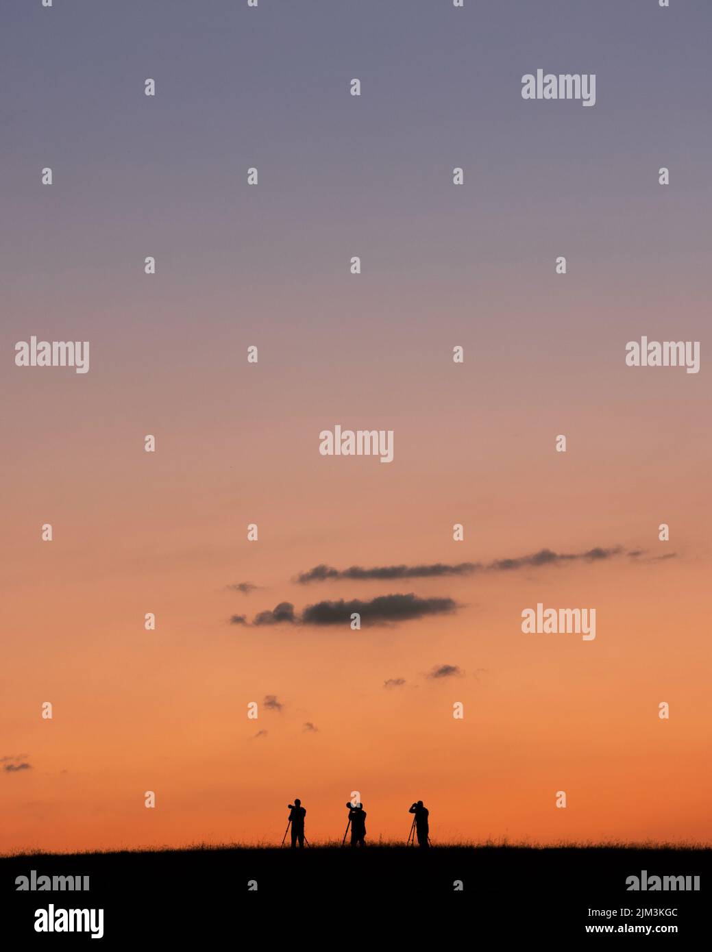 The three men taking pictures of scenic sunset with professional ...