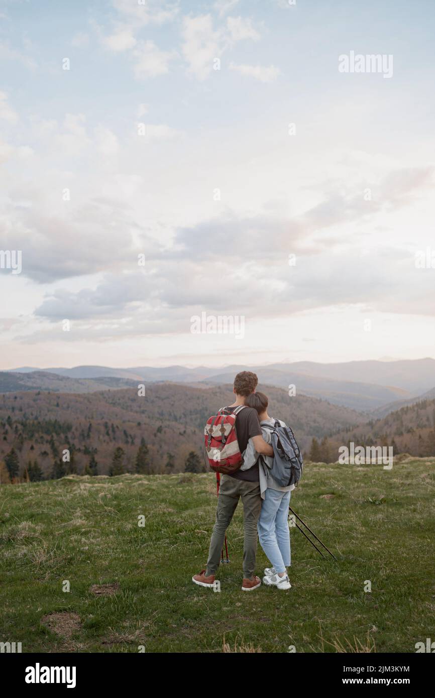 Rear on couple standing on top of mountain and enjoying beautiful view ...