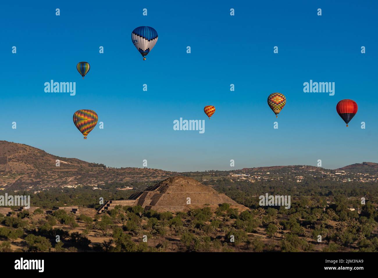 A distant view of colorful hot air balloons flying over the Pyramid of ...