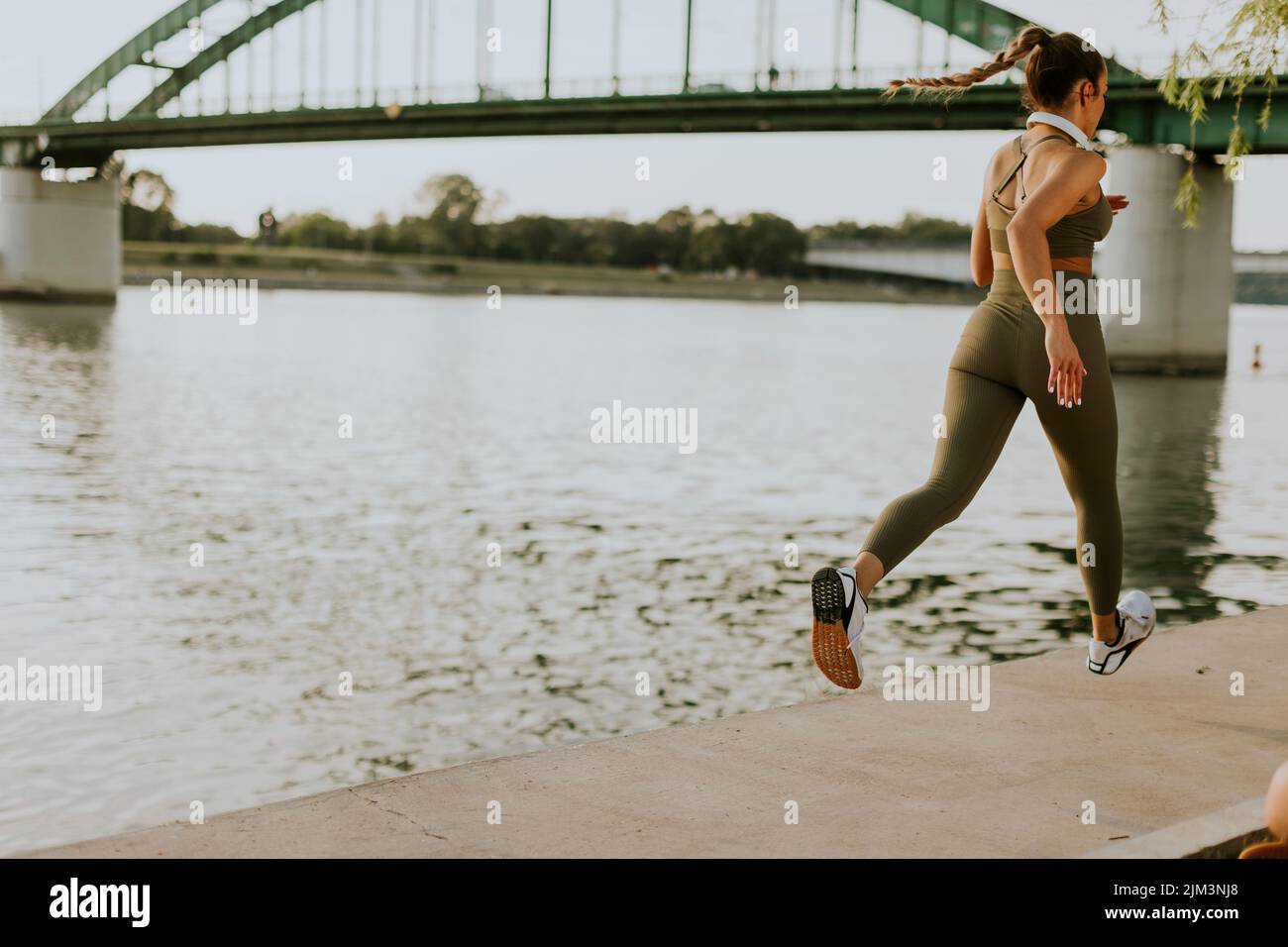 View at active young beautiful woman running on the promenade along the ...