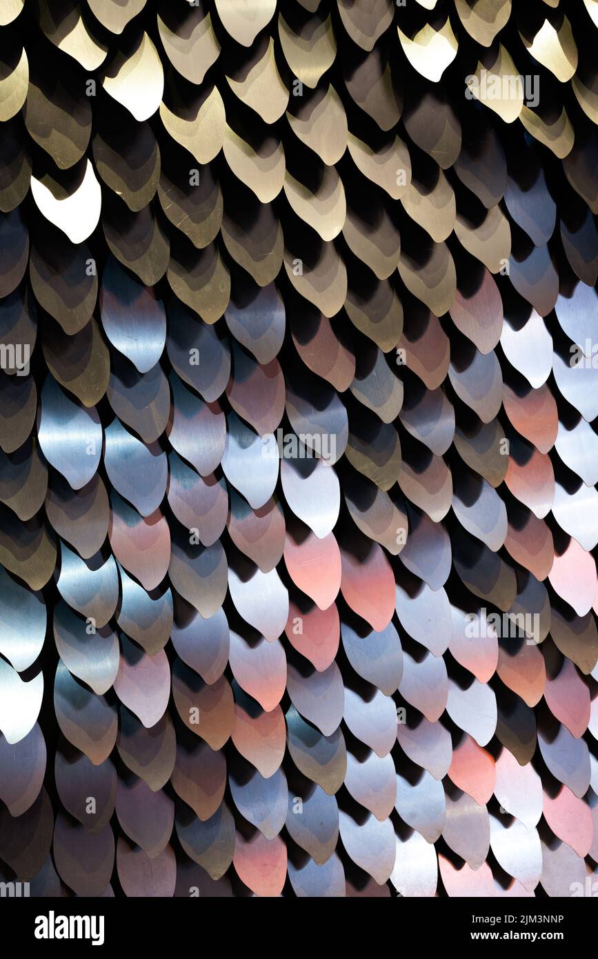 A vertical shot of metal scales reflecting different colors. A ...