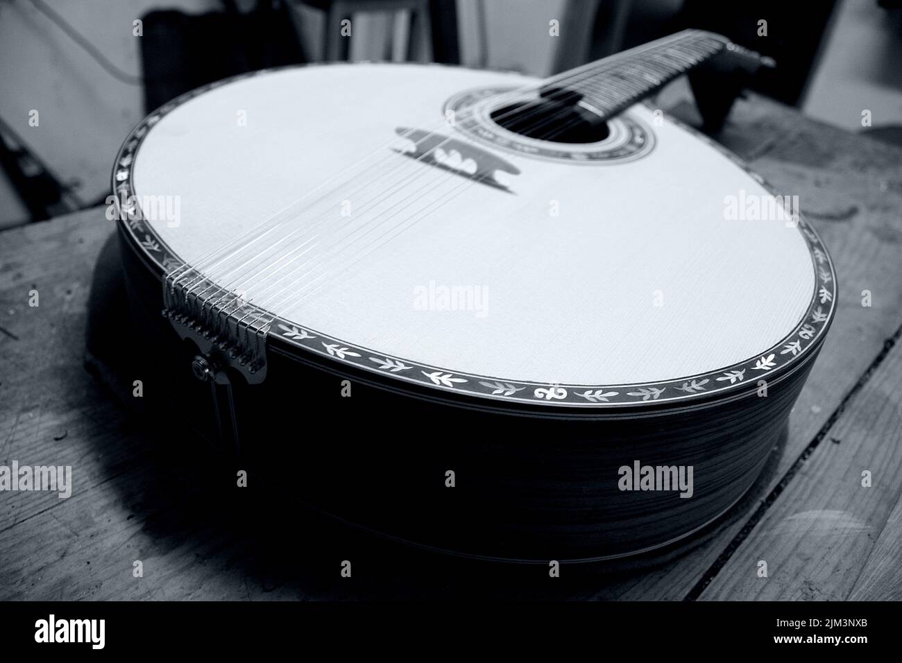 A grayscale of a beautiful mandolin with flower ornaments on a wooden ...