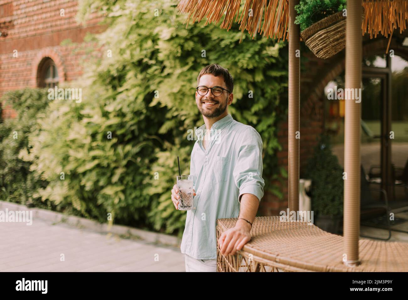Handsome young man drinking fresh cold lemonade at the pool bar Stock ...