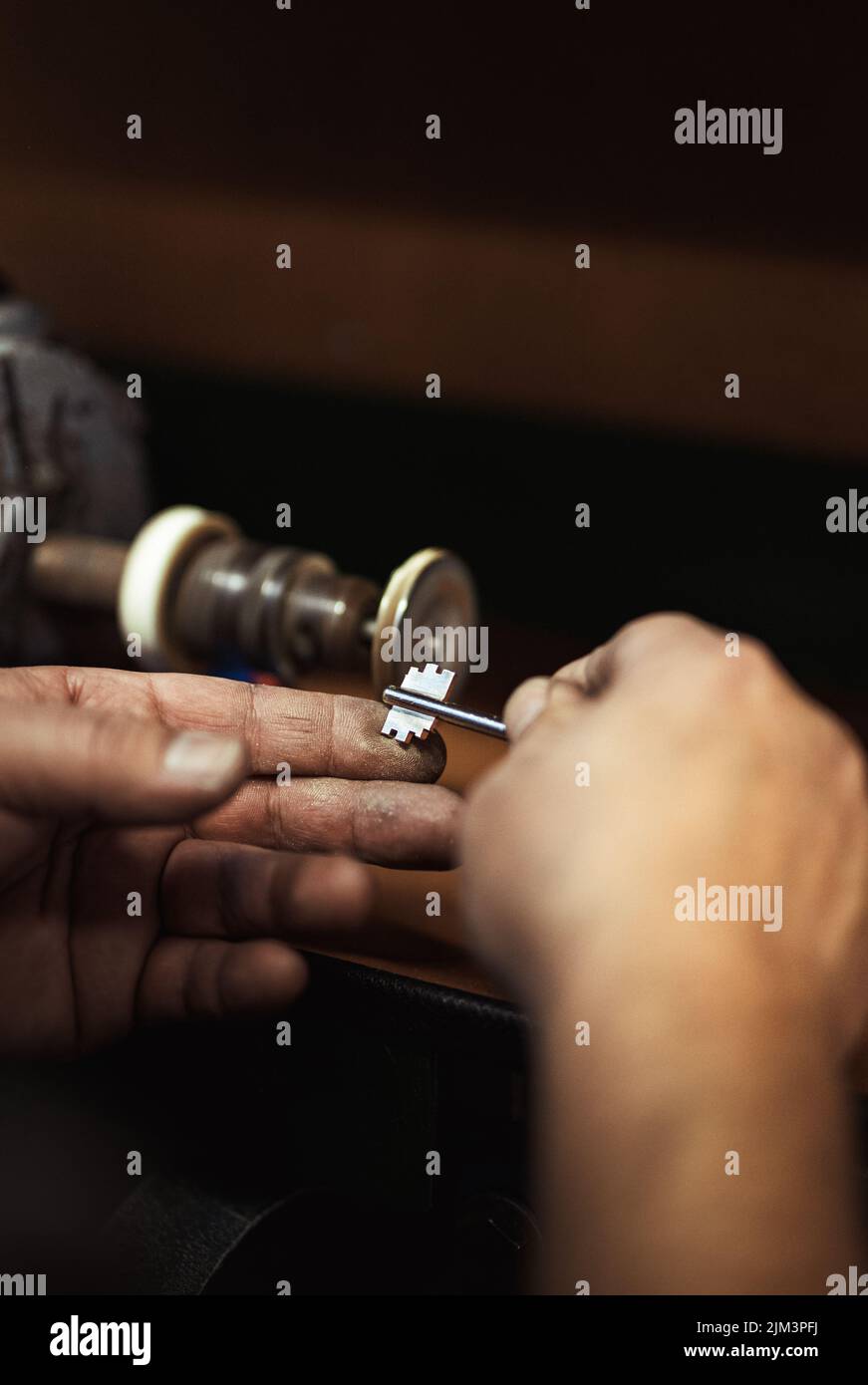 A vertical closeup shot of a locksmith's hands making a key Stock Photo ...