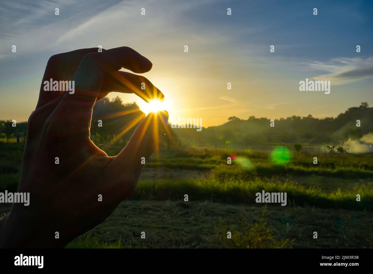 A view of a hand trying to catch the sun in a beautiful meadow with ...