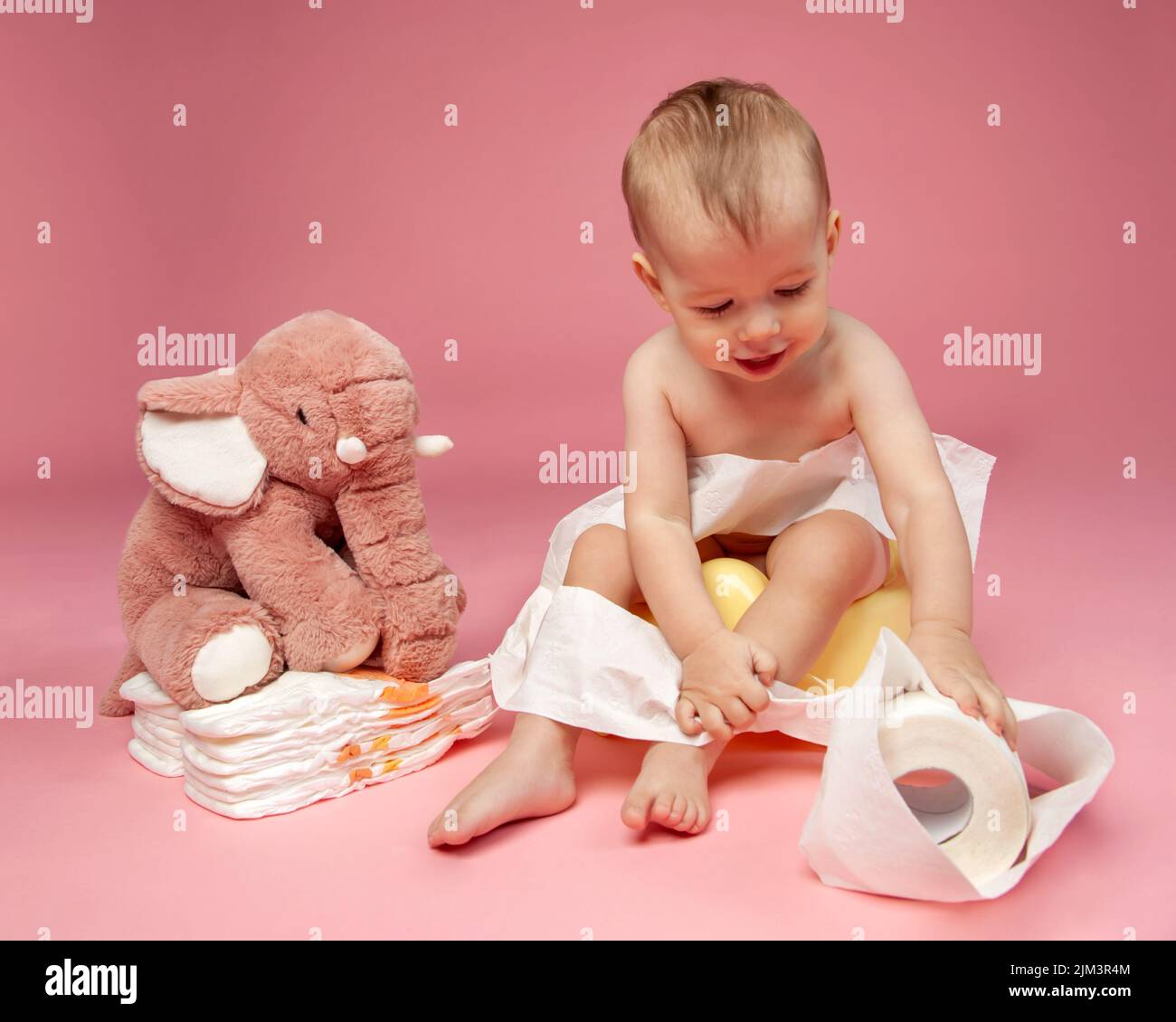 A cute little baby boy sitting on a potty and playing with a toilet ...