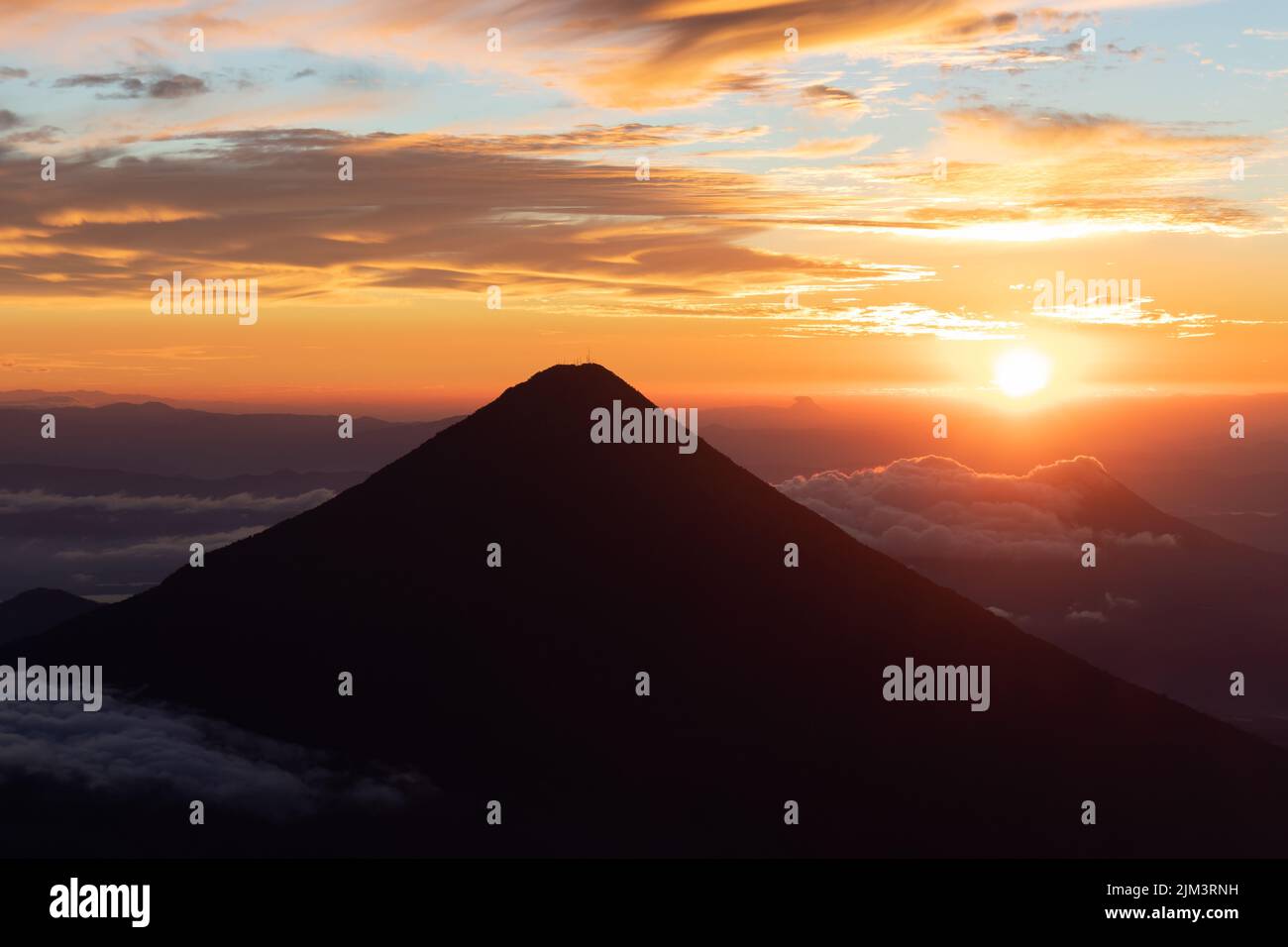 Silhouette of volcano de agua at firey orange sunrise seen from the top ...