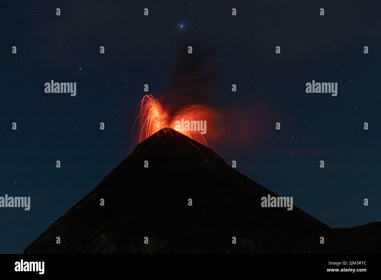Volcano fuego erupting with orange lava explosion at night below stars ...