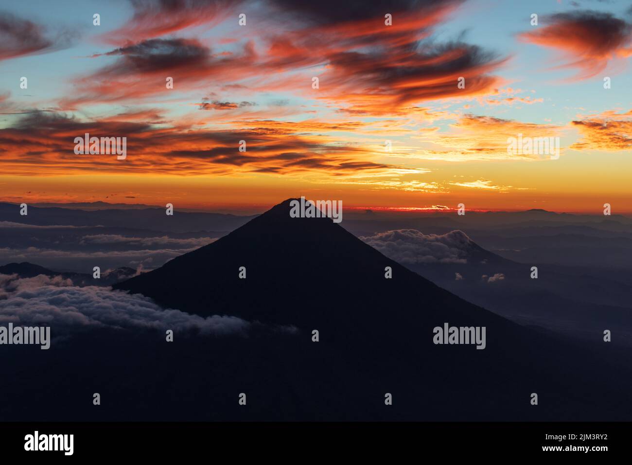 Silhouette of volcano de agua at firey orange sunrise seen from the top ...