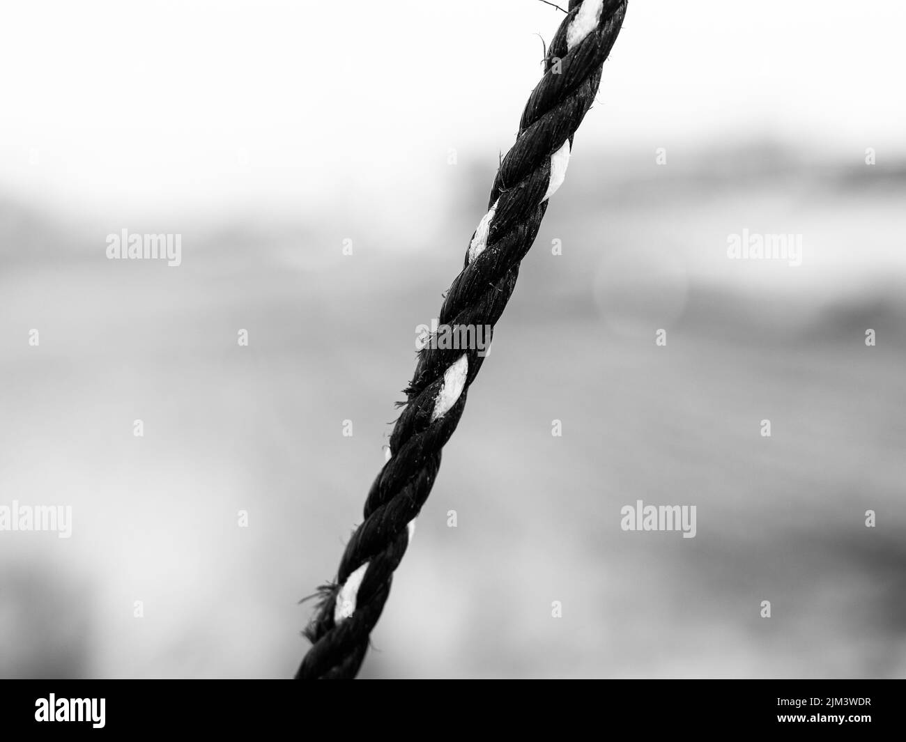 A grayscale closeup shot of a rope texture with blurred gray background ...
