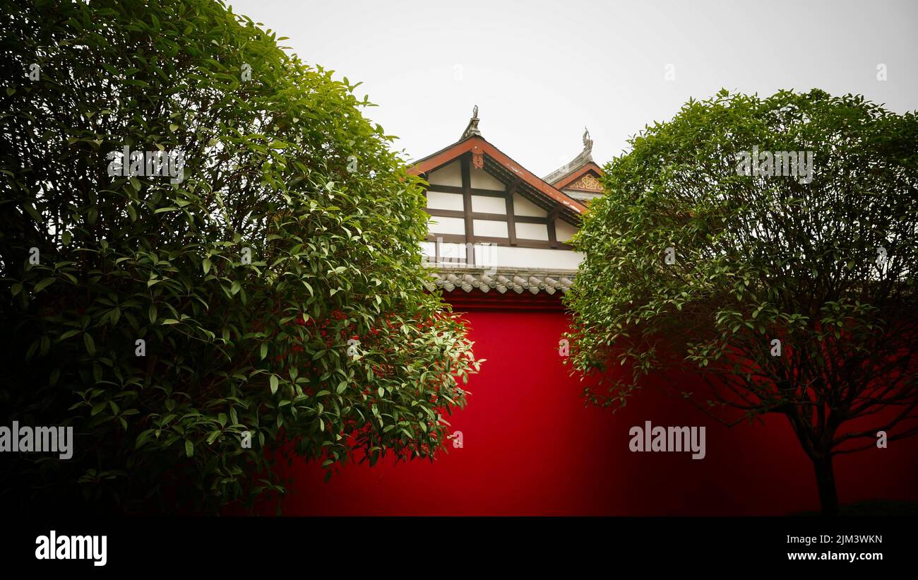 A red building in a Japanese style with shaped trees in front Stock ...