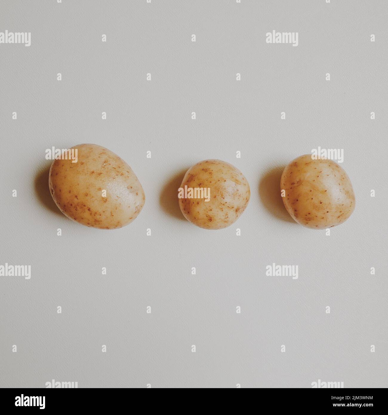 A top view of three potatoes on an off-white background Stock Photo - Alamy