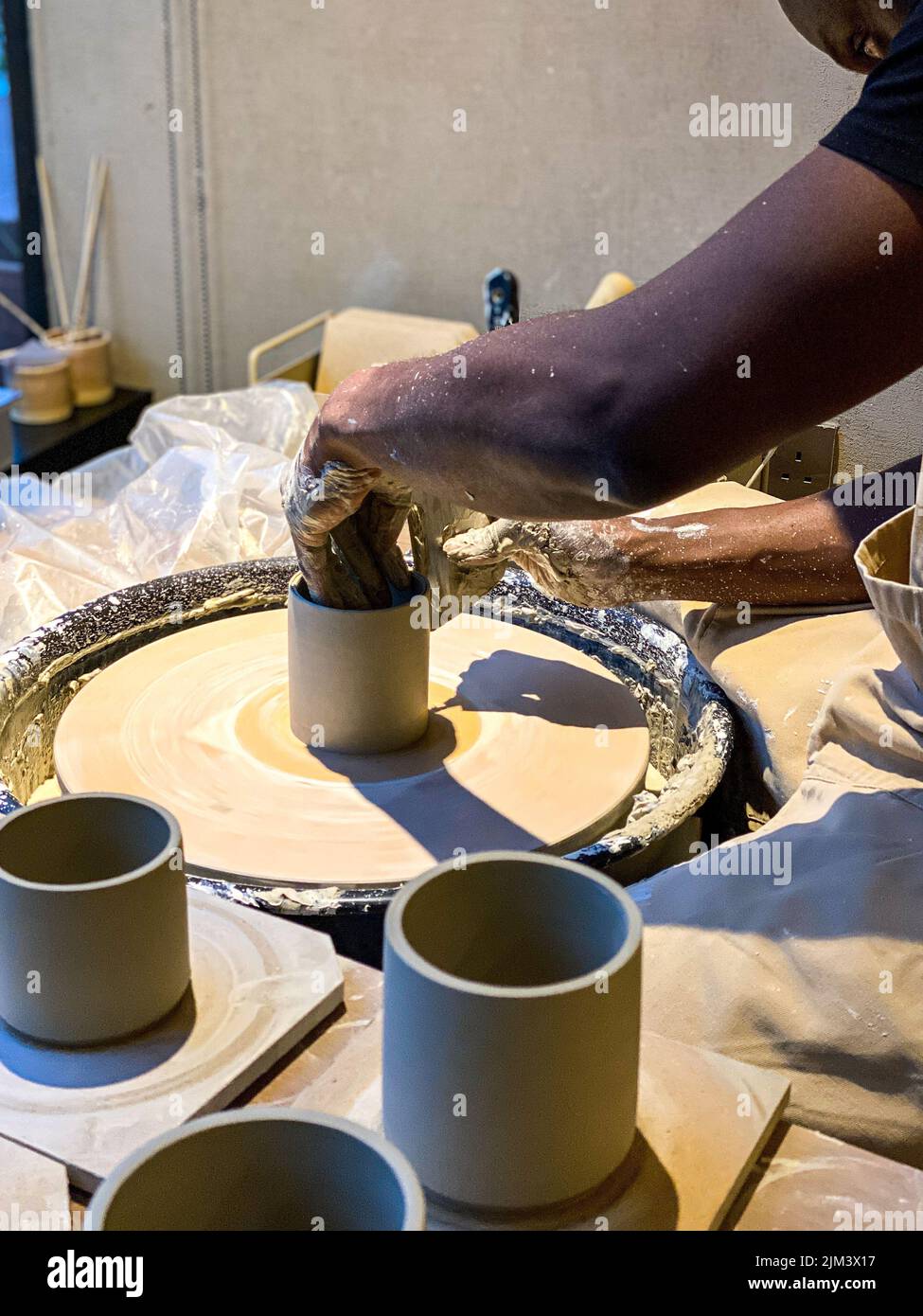 A man throwing a clay mug on a potters wheel Stock Photo - Alamy