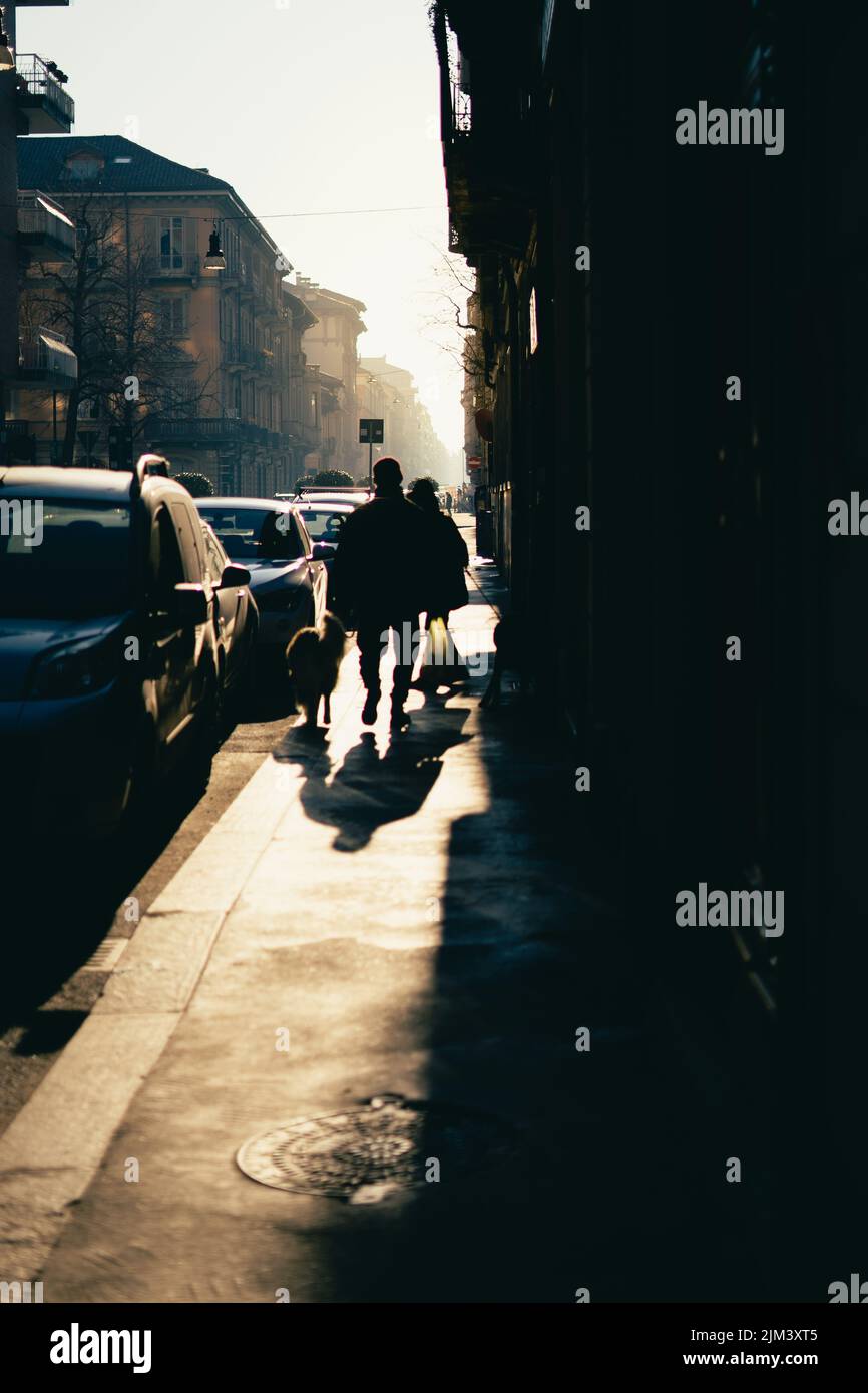 A vertical shot of people's silhouettes walking by the street between ...