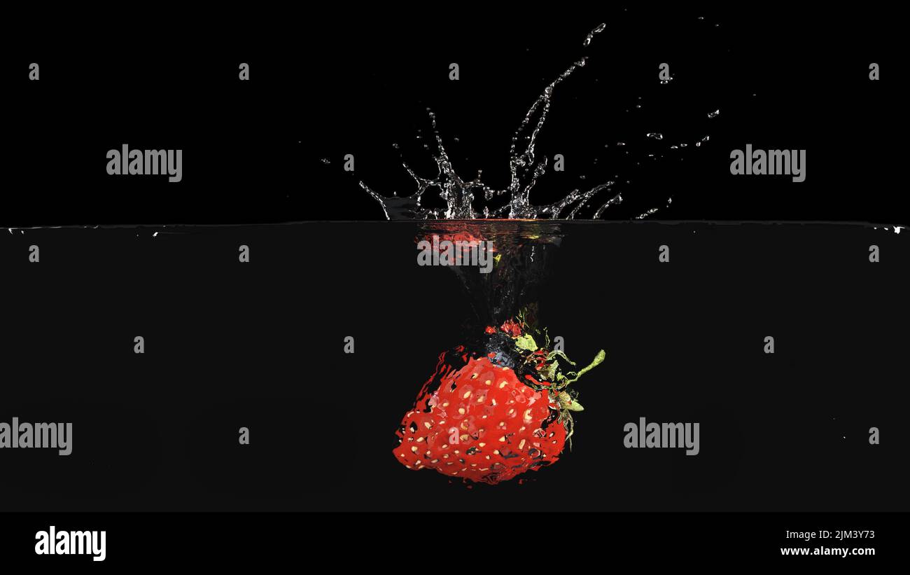 A red ripe strawberry falling into the water and splashing it on a ...