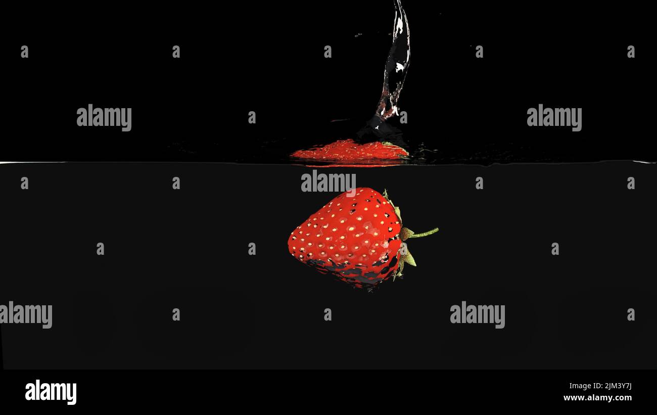 A red ripe strawberry falling into the water and splashing it on a ...