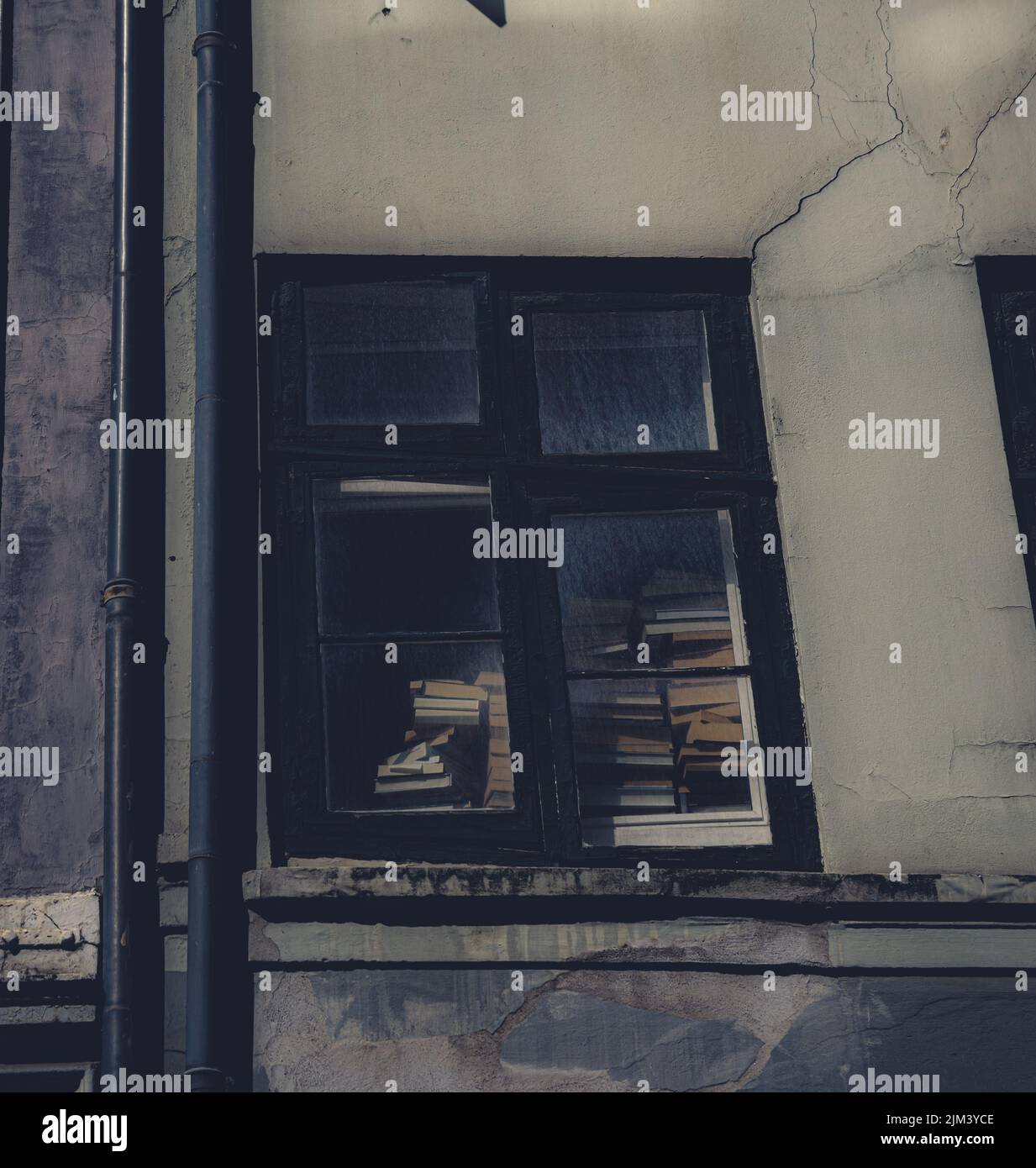 A closeup of a window with black frames on an old weathered building ...