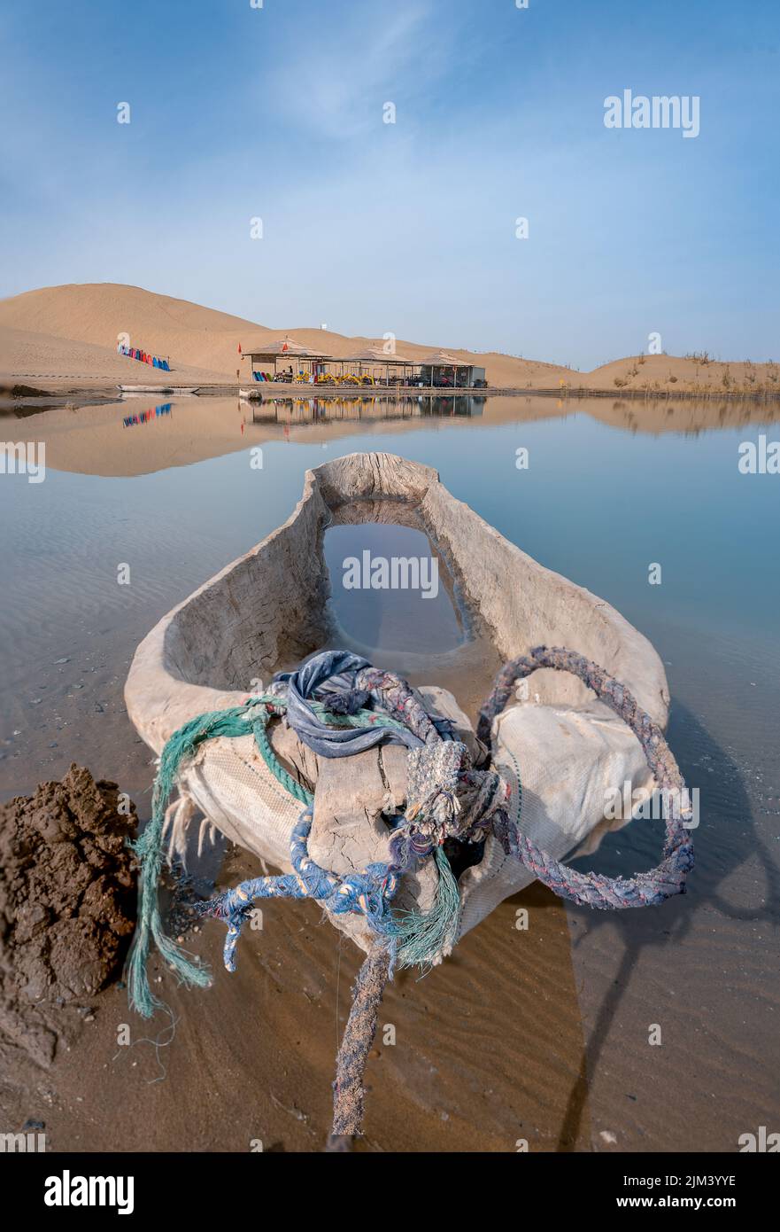 An old wooden boat with some water inside left on peaceful lakeshore ...