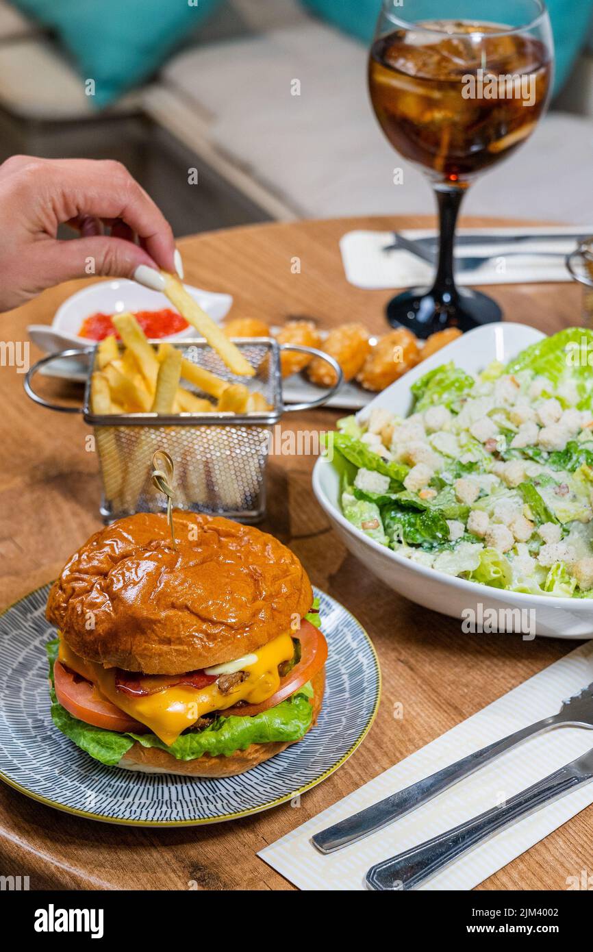 Cheeseburger with tomato and brioche bread, caesar salad, french fries ...