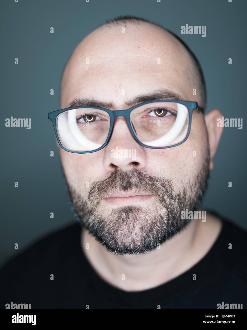 A portrait of a man with a beard wearing glasses and wearing a black t ...