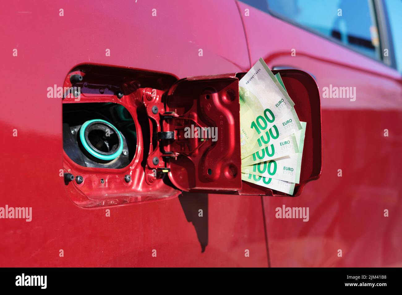 A car's open fuel tank with a bundle of one hundred euro banknotes in ...