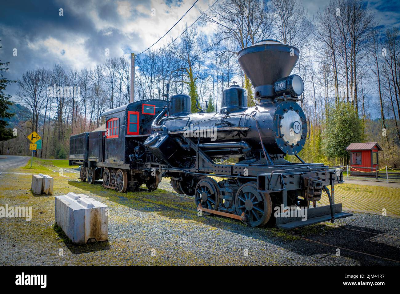 The vintage locomotive against the background of trees and cloudy sky ...