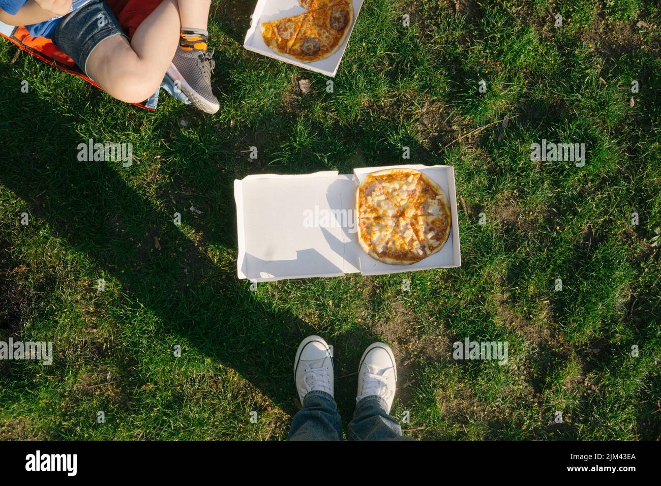 A top view of two people and pizza on green grass background Stock ...