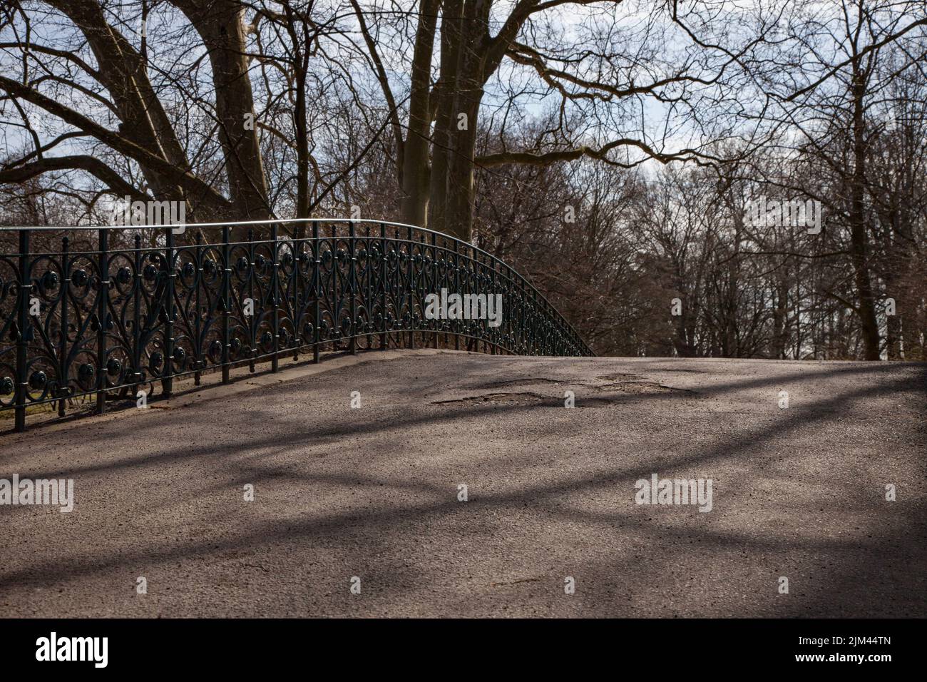 A park view with an empty bridge surrounded by leafless trees Stock ...