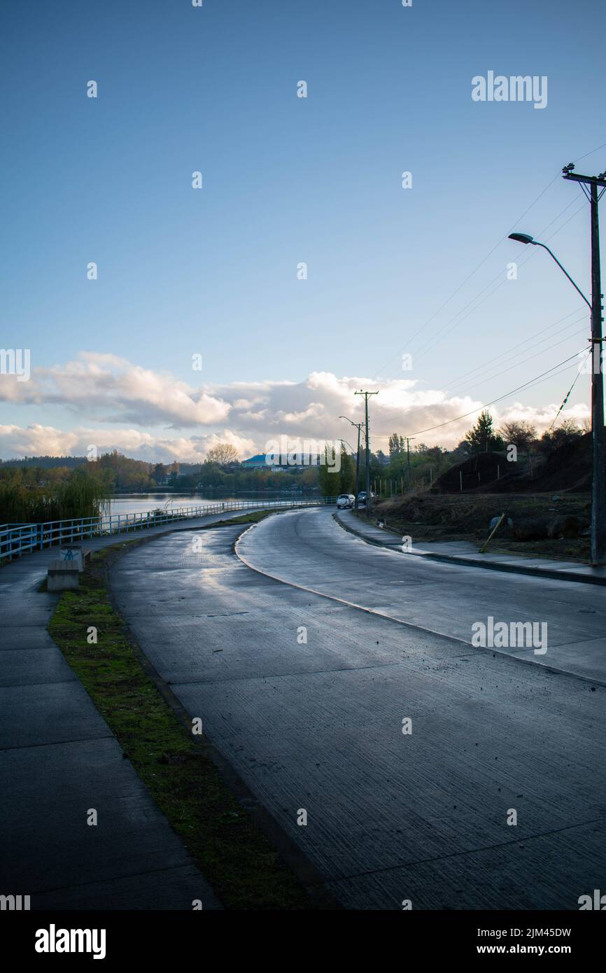 A vertical view of a winding asphalt road on the lakeshore on a cloudy ...