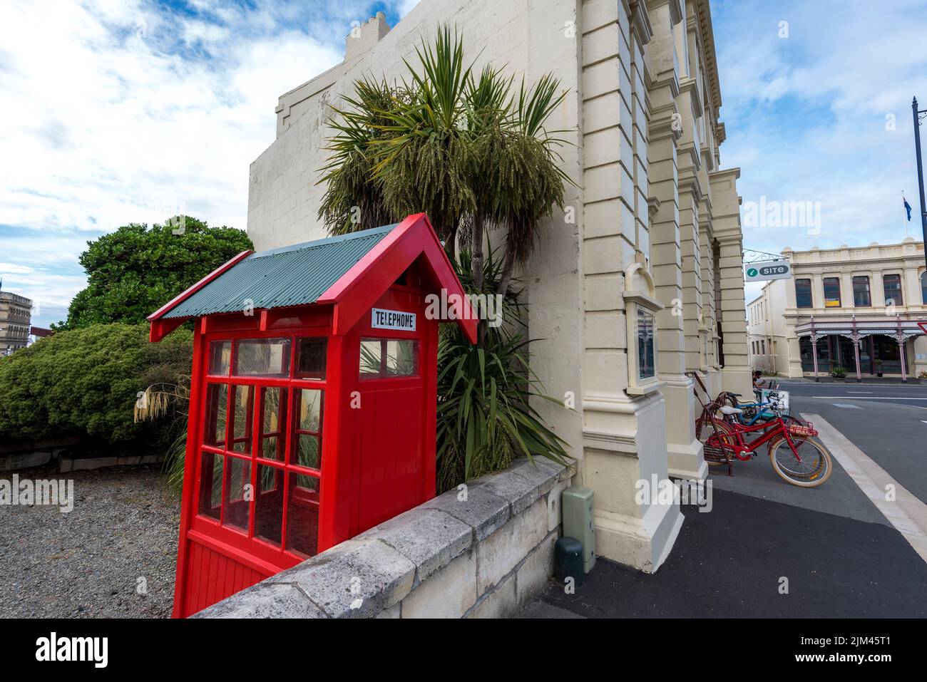 An old red telephone booth in the corner of a white building near a ...