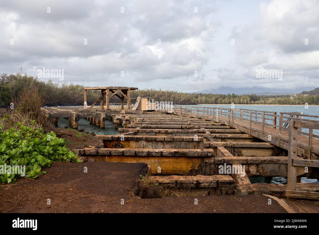 Remnants of the old dilapidated shabby dock in Kauai under a cloudy sky ...
